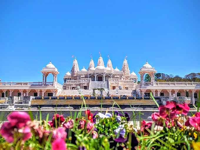 Those vibrant flowers frame hand-carved marble spires that look like they belong in a Bollywood dream sequence.