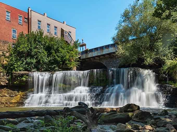 Downtown meets nature in this stunning cascade where brick buildings frame rushing water like an urban postcard.