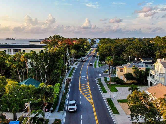 Golden hour transforms this coastal road into a postcard, where tree-lined streets meet waterfront living in perfect harmony.
