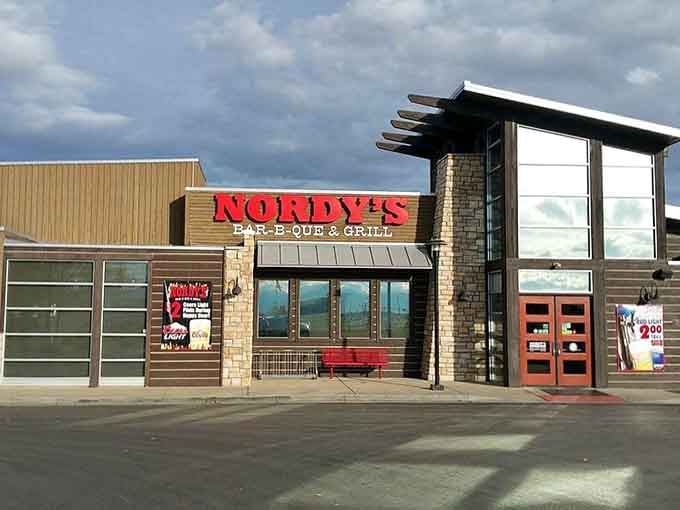 That bold red sign against dramatic Colorado skies promises smoky treasures waiting inside this modern BBQ haven.