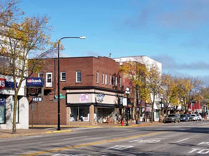 Classic brick storefronts line the street where autumn leaves frame a downtown that remembers when Main Street mattered most.