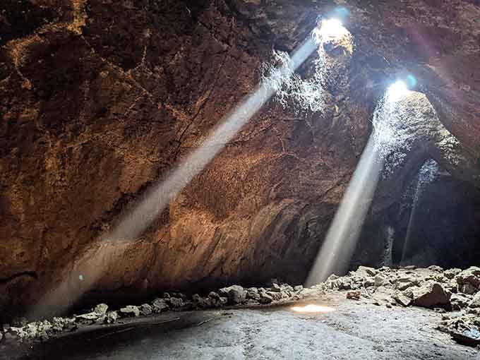 Nature's own cathedral lighting: twin beams of sunlight pierce the darkness like spotlights on a stage.