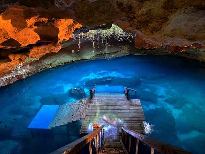That wooden dock leads you into an underground wonderland where stalactites drip and crystal-clear water beckons adventurers.