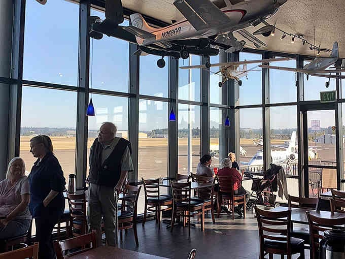 Floor-to-ceiling windows frame taxiing aircraft like living artwork while diners enjoy the ultimate plane-spotting lunch experience.
