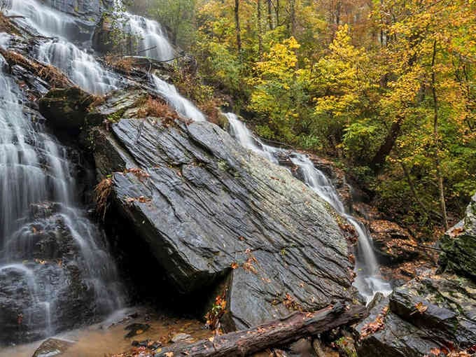 Autumn paints the rocks gold while water dances over ancient stone, creating a masterpiece that changes with every season.