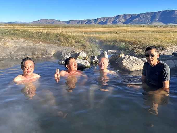 Four happy soakers proving that the best conversations happen when you're neck-deep in warm mineral water together.