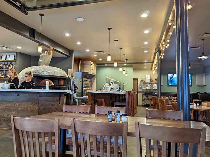 Warm rustic interior at Camporosso showcases wood-fired oven, cozy seating, and friendly atmosphere perfect for sharing pizza with friends tonight.