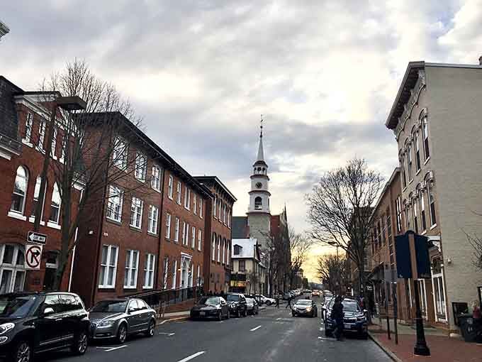 That church steeple rising above historic storefronts proves some towns still remember what charm actually means.