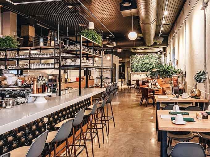 Industrial chic meets botanical garden in this stunning space where polished concrete floors and lush greenery create breakfast magic.