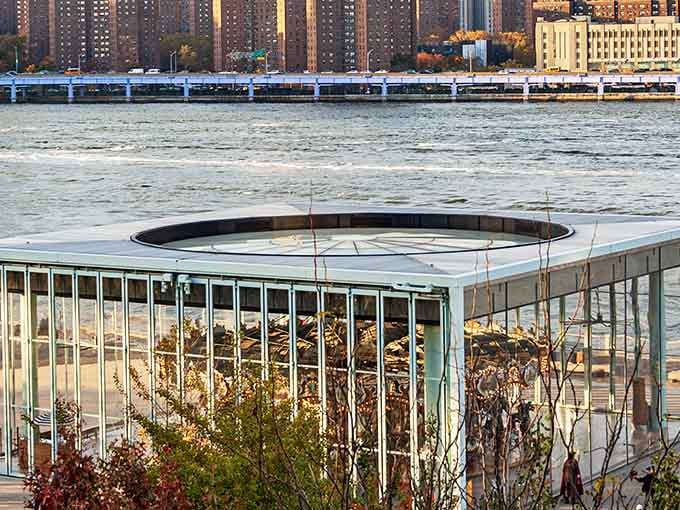 From across the park, the glass pavilion frames the carousel like a precious jewel worth discovering.