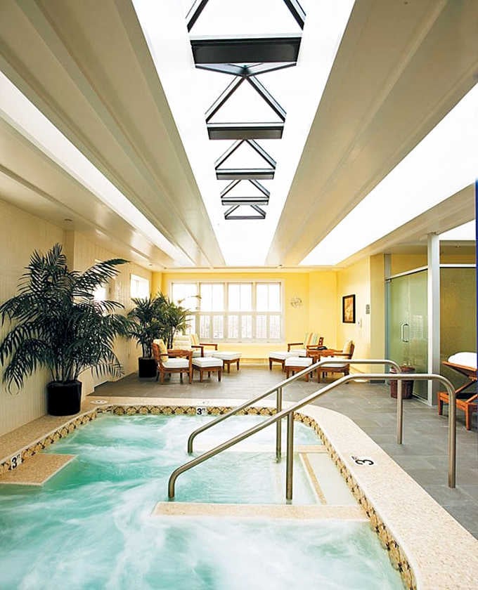 Natural light floods through geometric skylights, turning this sunny hydrotherapy space into pure suburban serenity.
