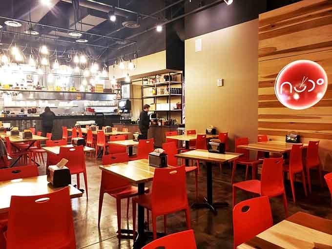 Modern meets cozy with those cherry-red chairs and warm wood tones creating the perfect slurp sanctuary.