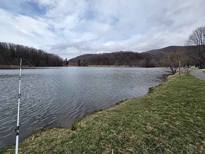 Mountains frame this peaceful lake where fishing poles lean hopefully and reflections double nature's artistry on calm water.