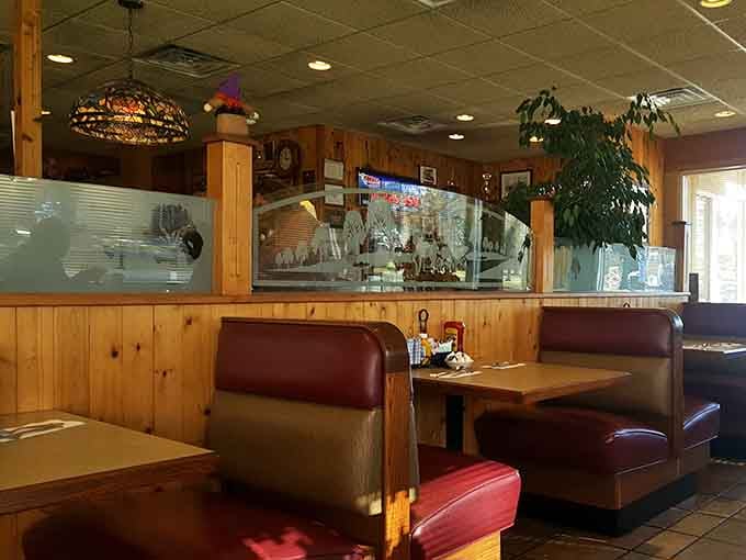 Wood paneling, burgundy booths, and etched glass dividers create the kind of atmosphere where breakfast feels like coming home.