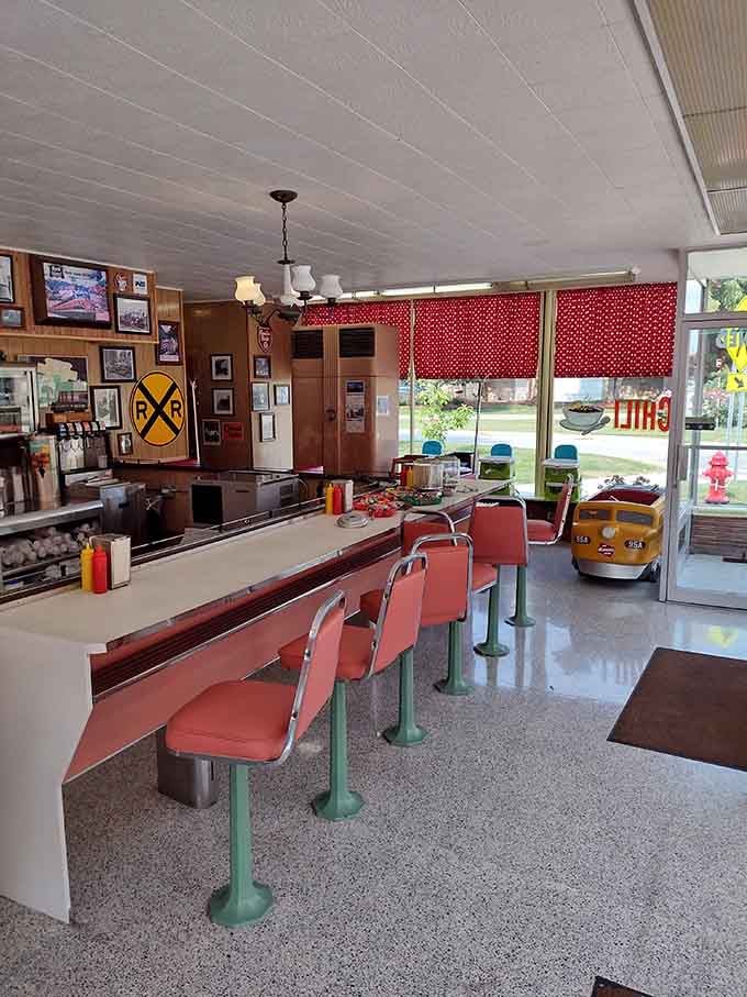Red vinyl stools line a counter where model trains deliver dinner, proving someone finally cracked the code on perfect dining.