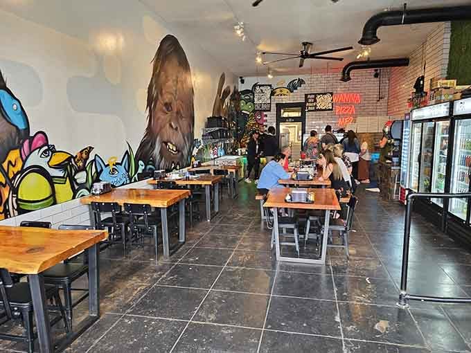 Colorful murals and wooden tables create a vibe that's equal parts playful pizzeria and cryptid enthusiast's dream hangout.