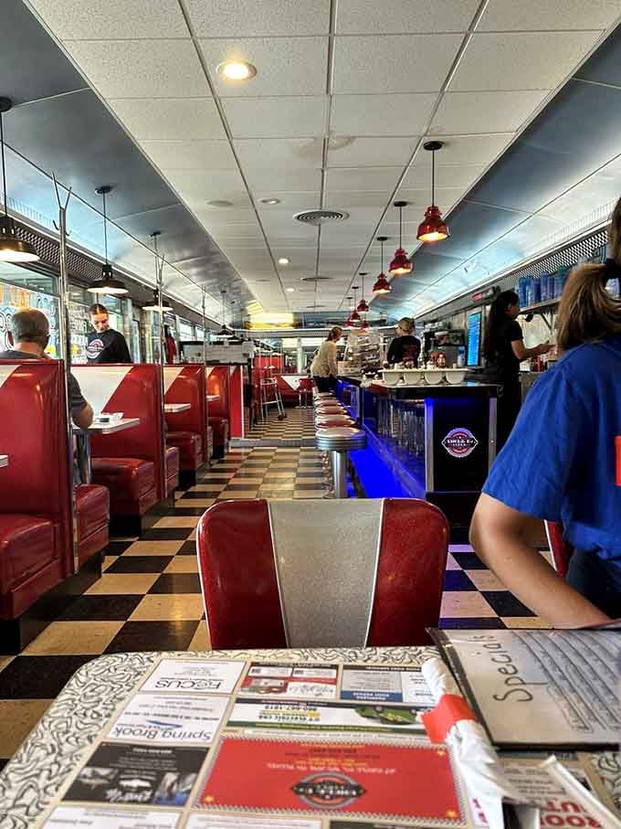 Red vinyl booths, checkered floors, and pendant lights create the timeless diner atmosphere your grandparents would recognize instantly.
