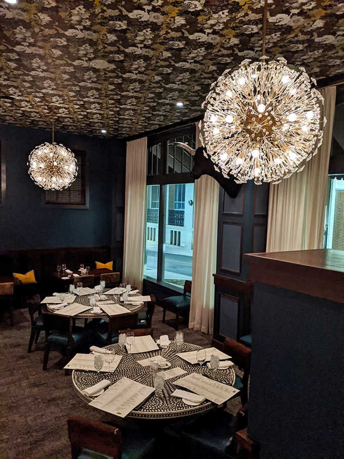 Dark walls and dramatic lighting create an intimate atmosphere where every dinner feels like a special occasion.