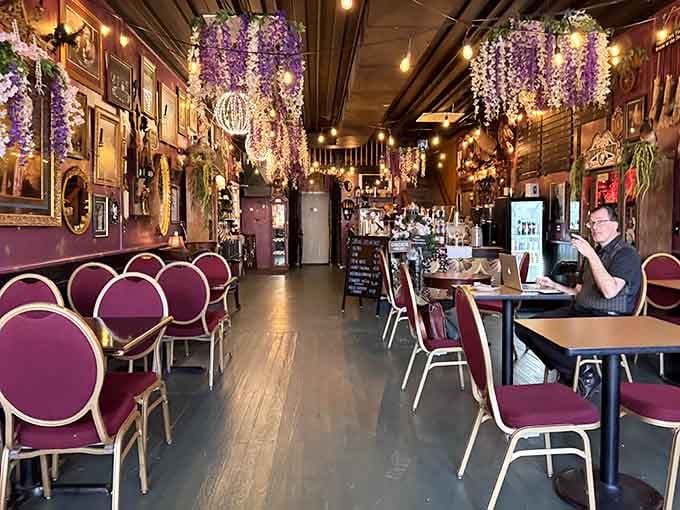 Cascading purple blooms overhead transform this coffee haven into an enchanted garden that never closes.