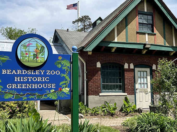 The Historic Greenhouse sign welcomes you to a tropical escape where exotic plants thrive behind classic brick walls.