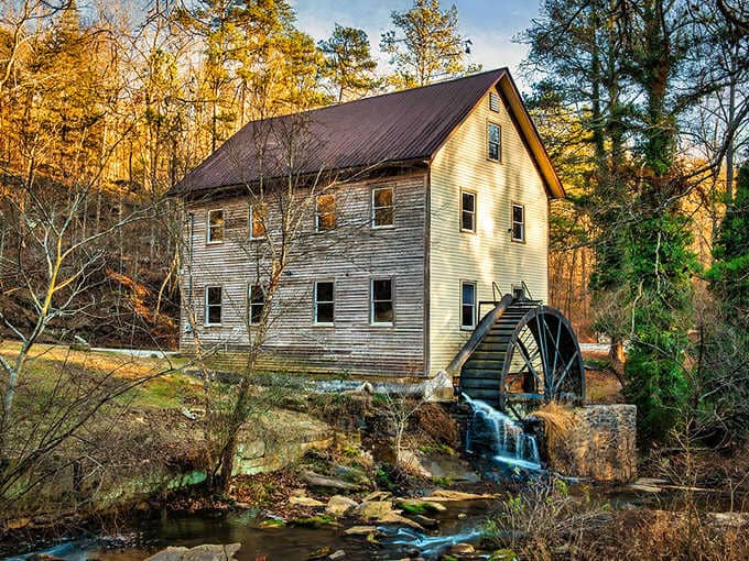 Golden light bathes this abandoned mill where the waterwheel still turns, grinding nothing but memories and atmosphere.