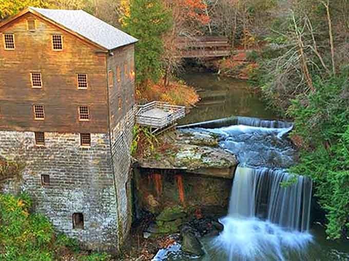 Autumn colors embrace the historic grist mill while water flows peacefully beside this timeless scene.