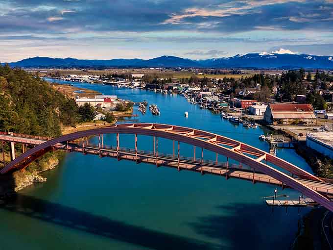 Rainbow Bridge arching over turquoise water with mountains watching &ndash; La Conner knows how to frame a view.