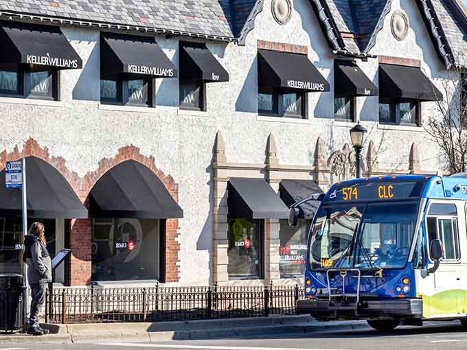 That blue bus gliding past classic storefronts proves small-town charm and modern convenience can absolutely coexist.