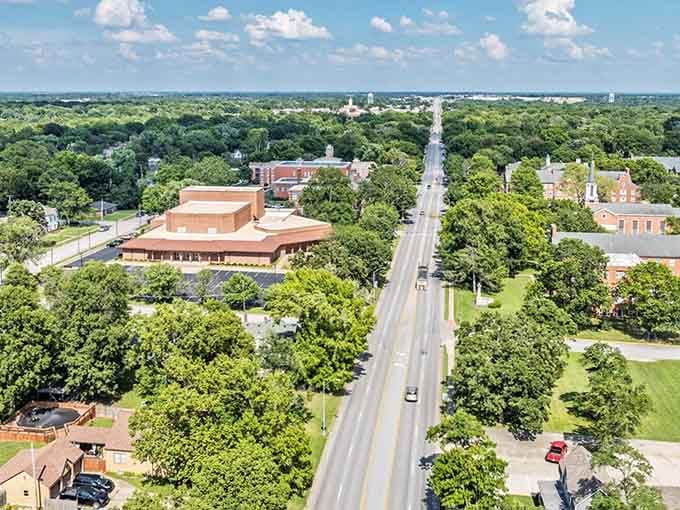 Tree canopies embrace this town from above, creating a green oasis that stretches toward the horizon.