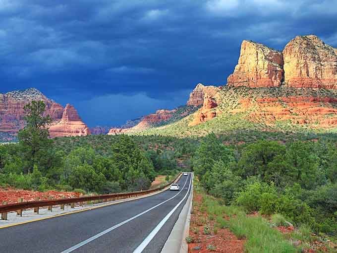 Clouds gathering over crimson formations turn an already dramatic landscape into pure theater you can drive through.