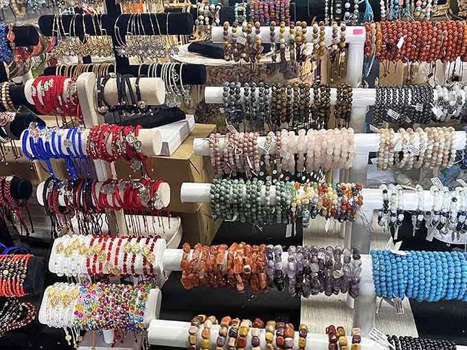 Beaded bracelets cascade in rainbow waves, each strand catching light like a miniature jewelry store exploded beautifully.