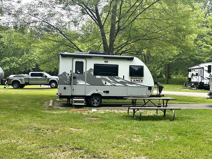 Shaded campsites nestled under towering trees offer the perfect blend of nature and modern camping convenience.