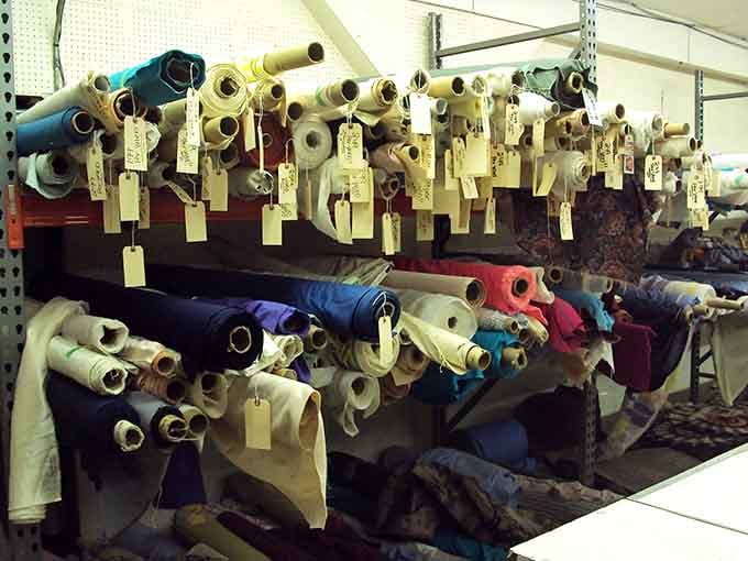 Fabric rolls stacked like a quilter's rainbow, each bolt tagged and waiting for creative hands.