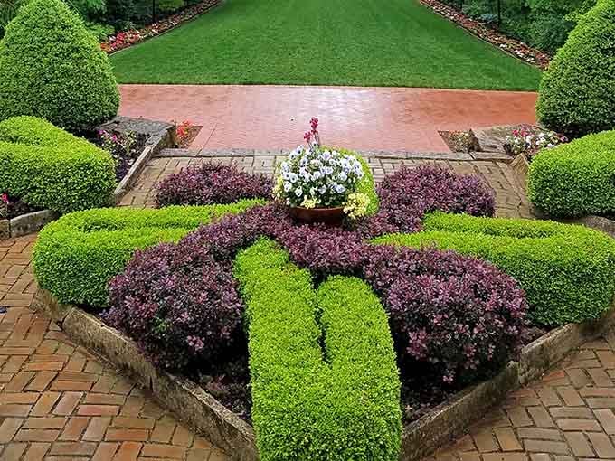 Beautifully sculpted hedges and vibrant purple shrubs create a stunning geometric masterpiece, perfect for a peaceful stroll through the grounds.
