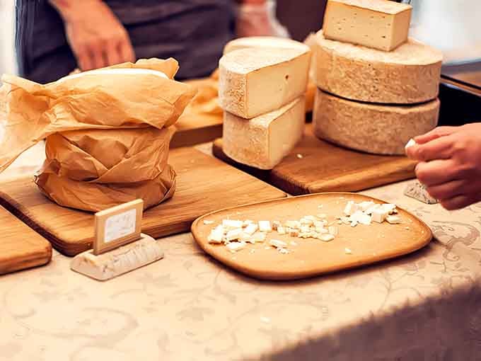 Wheels of artisanal cheese stacked like edible architecture, each one a masterpiece waiting to transform your next meal.
