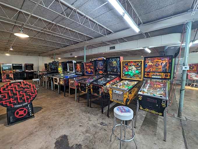 Classic pinball tables line up in formation, their artwork gleaming under industrial warehouse lighting and nostalgia.