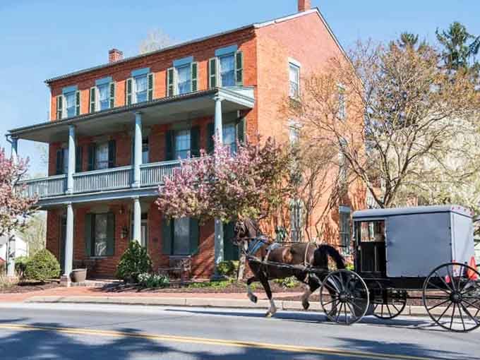Spring blossoms frame this brick beauty while a buggy passes by, mixing centuries in one charming snapshot.