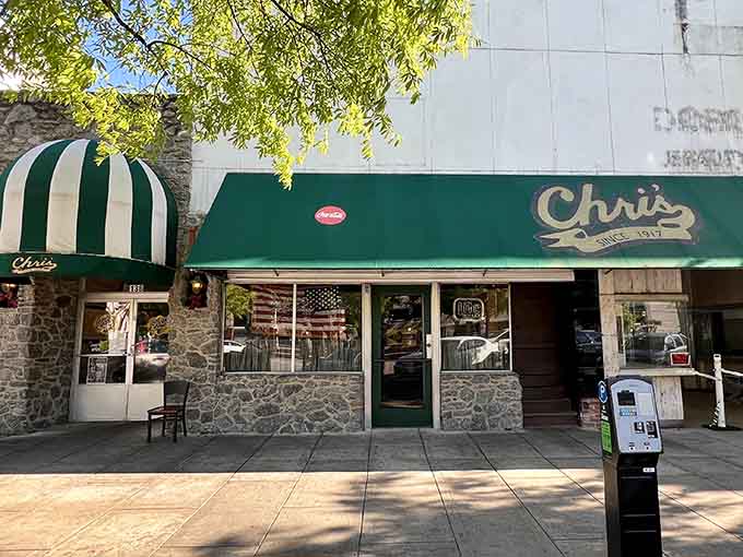 The striped awning and stone facade create a timeless streetscape that looks like it jumped from a Norman Rockwell painting.