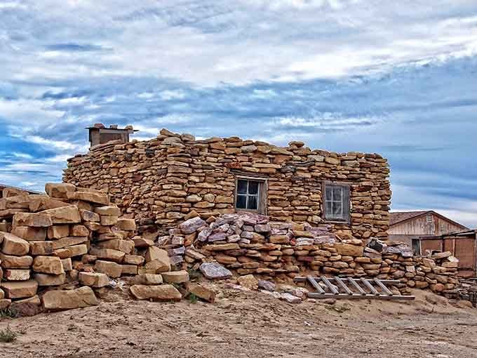 Ancient stone buildings rise from the mesa top, standing strong after nearly a thousand years of desert winds.