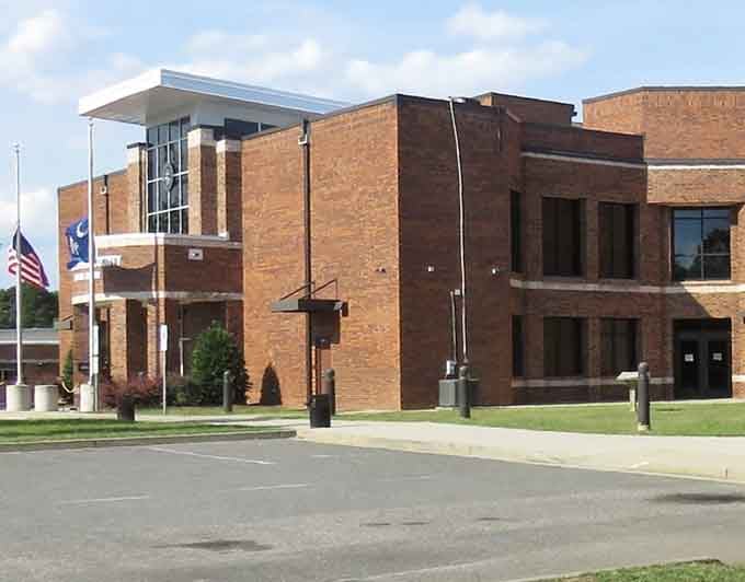 Modern civic architecture meets small-town pride with flags waving against a peaceful blue sky.