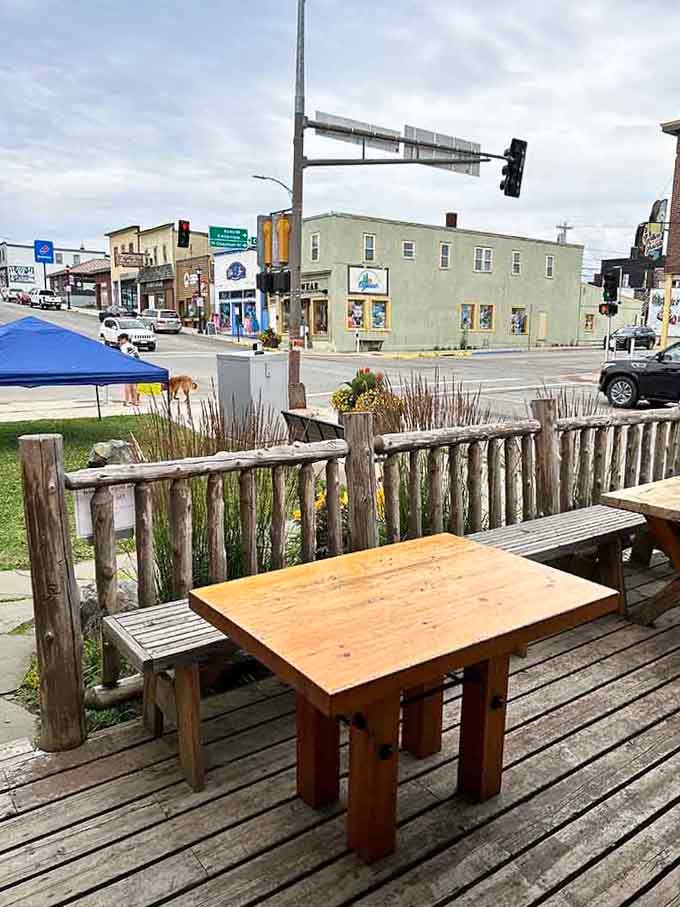 Rustic outdoor seating overlooks downtown life, perfect for coffee and people-watching on sunny mornings.