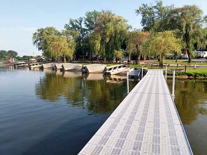 Graceful willows frame this peaceful boat launch where the dock stretches toward adventure like a welcome mat on water.