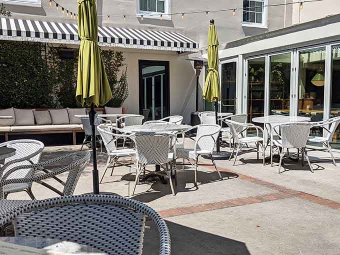 Parisian-style bistro chairs dot this sunny patio where black-and-white awnings provide shade for leisurely afternoon meals and conversation.