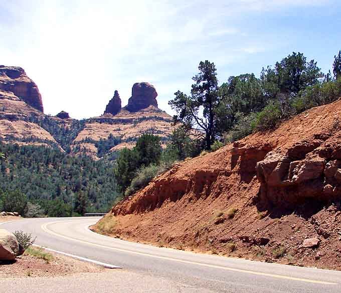 Winding through canyon walls where red earth meets green forest feels like discovering a secret passage through time itself.