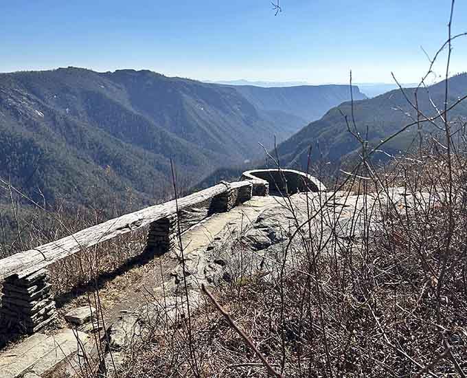 The gorge drops away beneath weathered stone, revealing layers of mountains that fade into misty blue distance.