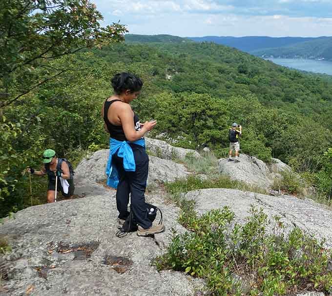 Hikers pause on sun-warmed granite to soak in sweeping views that stretch beyond the treetops for miles.