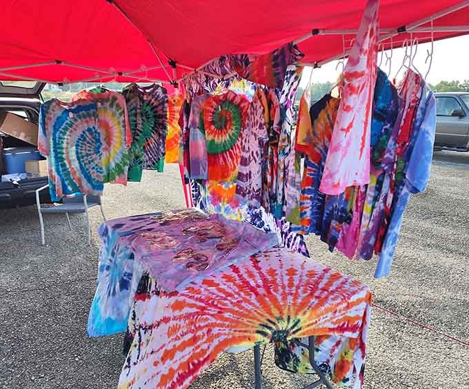 Tie-dye shirts explode with color under a red tent, bringing back memories of concerts and questionable fashion choices.