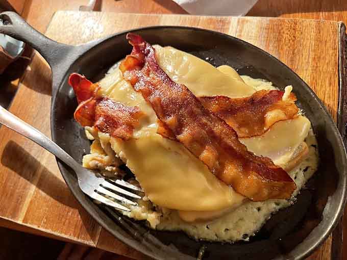 Bacon draped over perfectly cooked eggs like edible architecture, this skillet breakfast means serious business from the first bite.