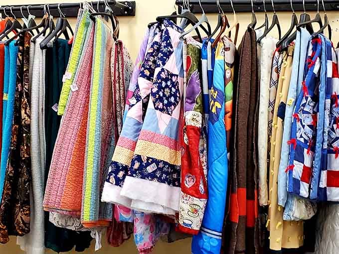 Vintage quilts and colorful throws hang like fabric art, each pattern telling stories of cozy nights past.