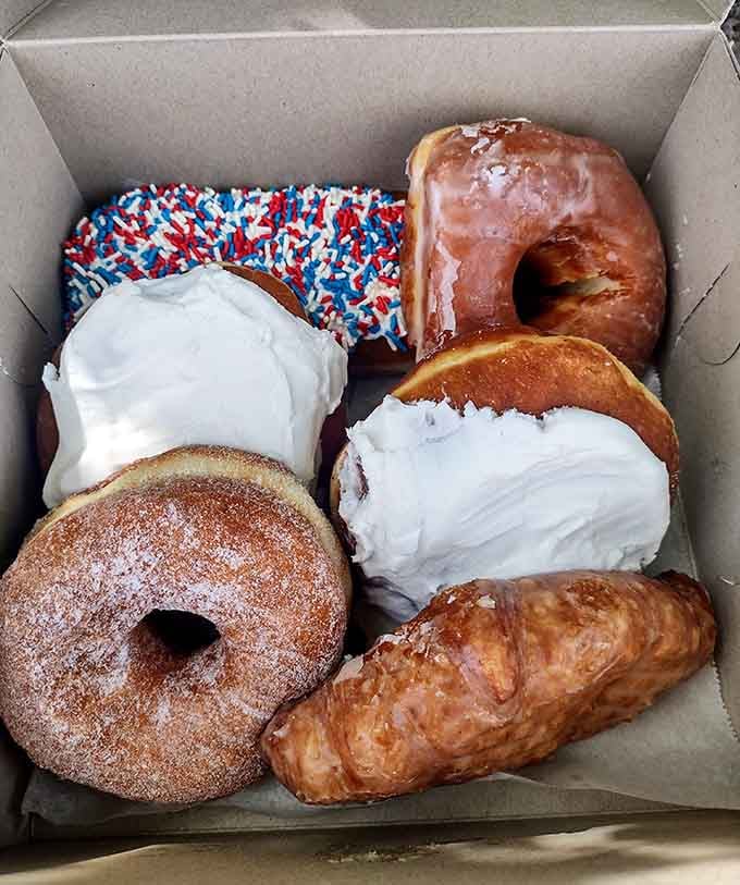 This box holds more joy than most people experience in a week: glazed, frosted, sprinkled, and absolutely perfect.